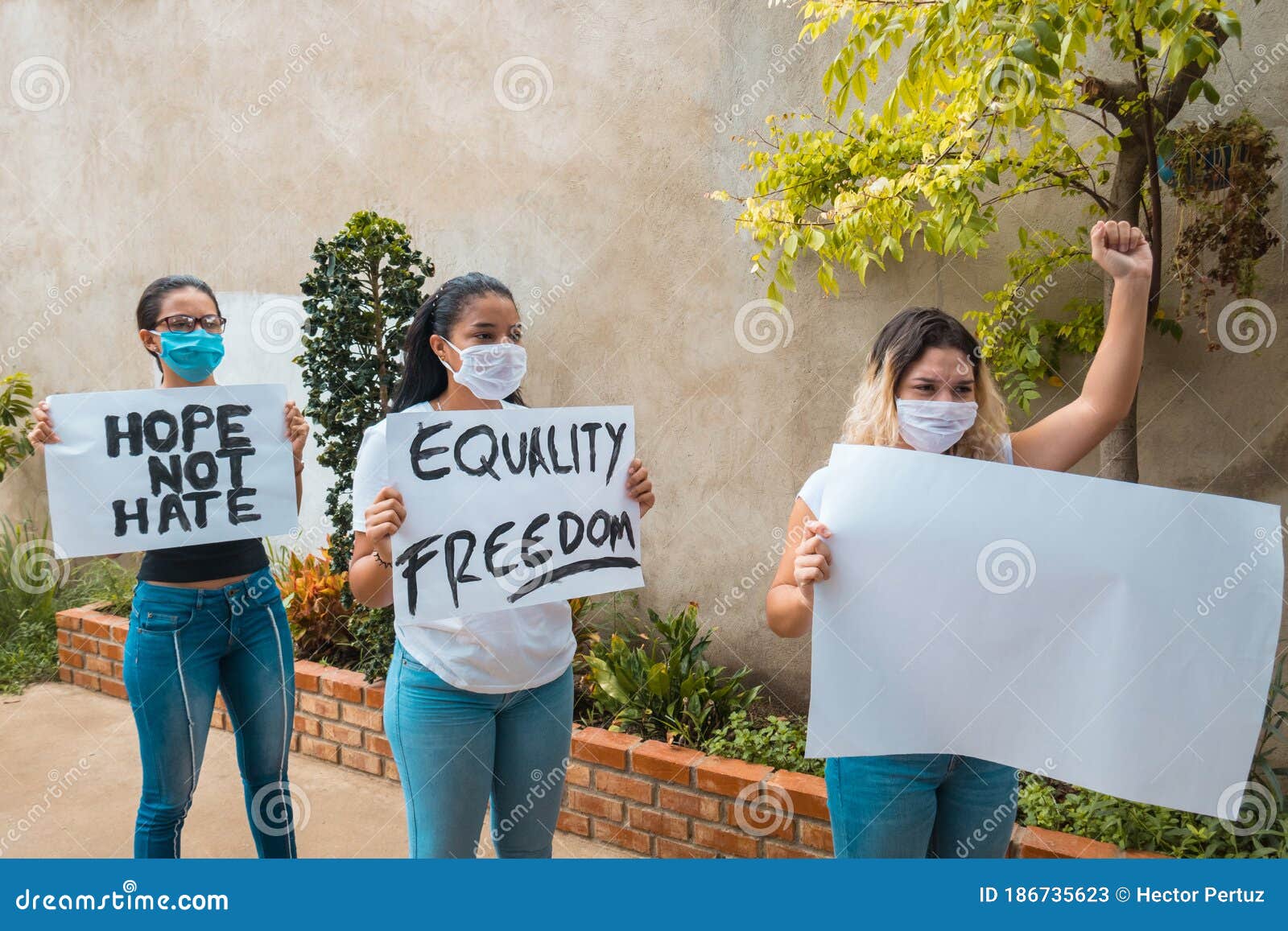 Three Young Hispanic Women at a Protest Holding Posters with Free Copy ...