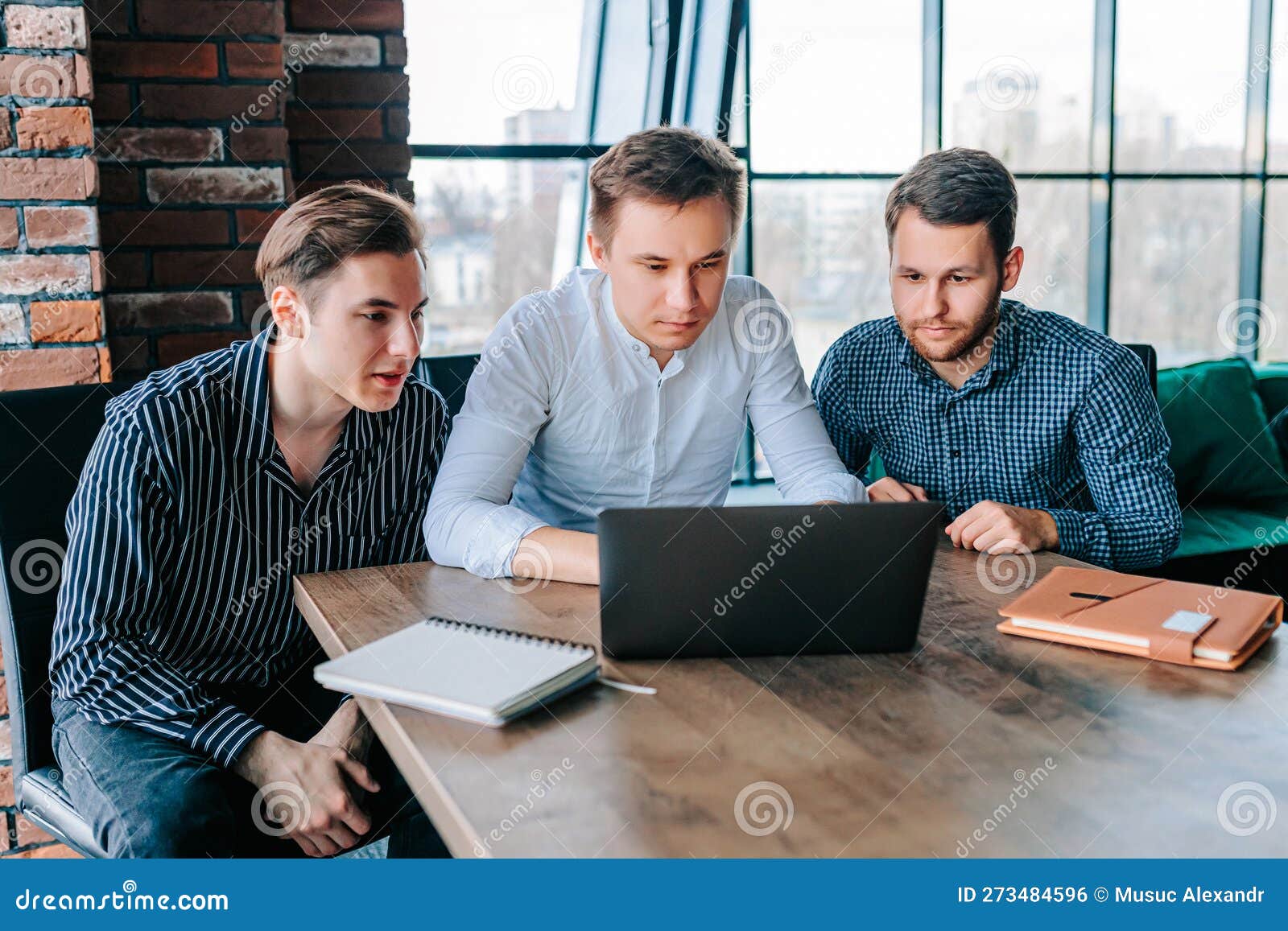 Three Young Men in an Office, Discussing Work Matters while Looking at ...