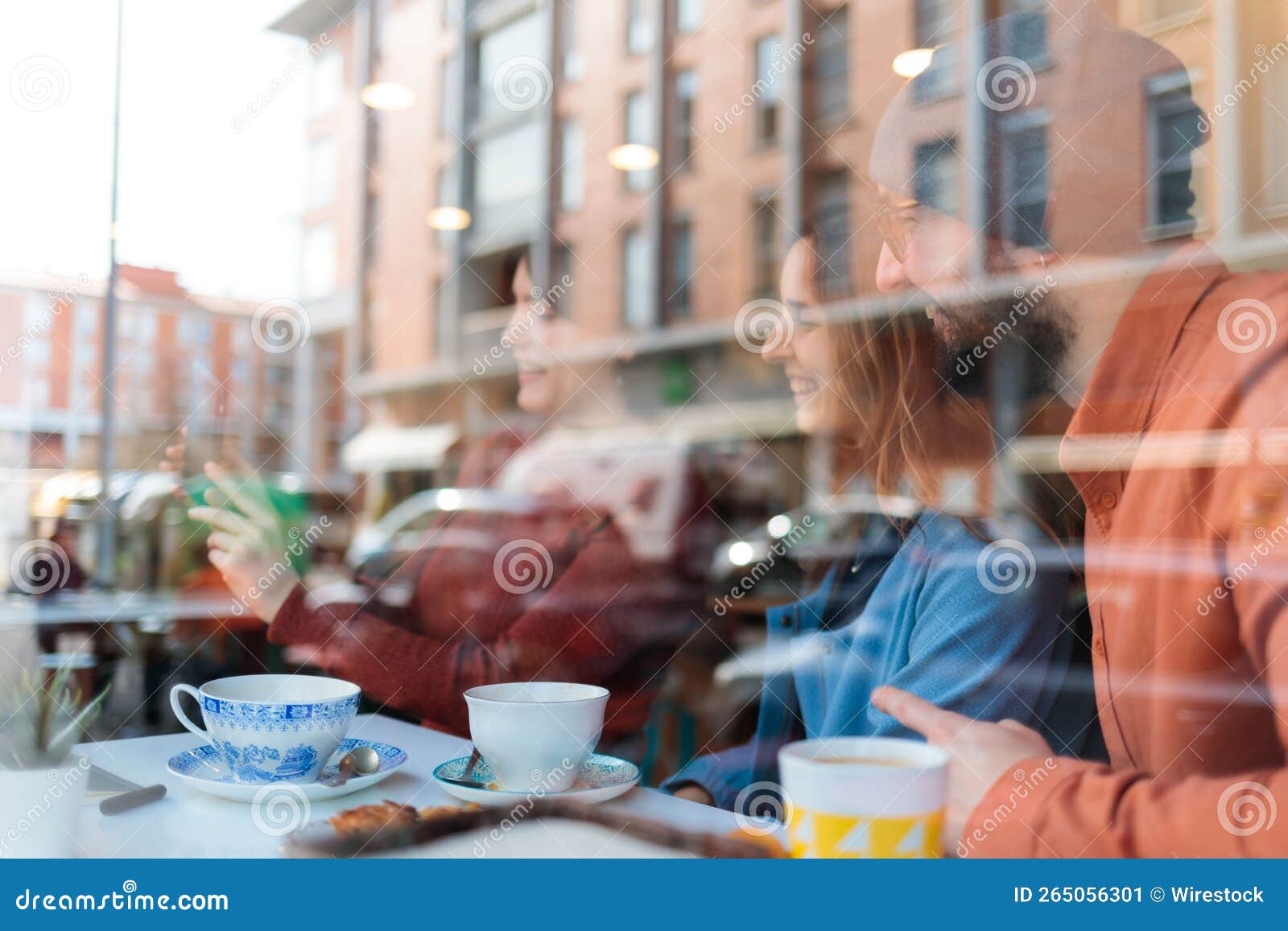Young People Sitting at a Cafe, Smiling, and Looking at Their Pictures ... Young People Sitting at a Cafe, Smiling, and Looking at Their Pictures ...