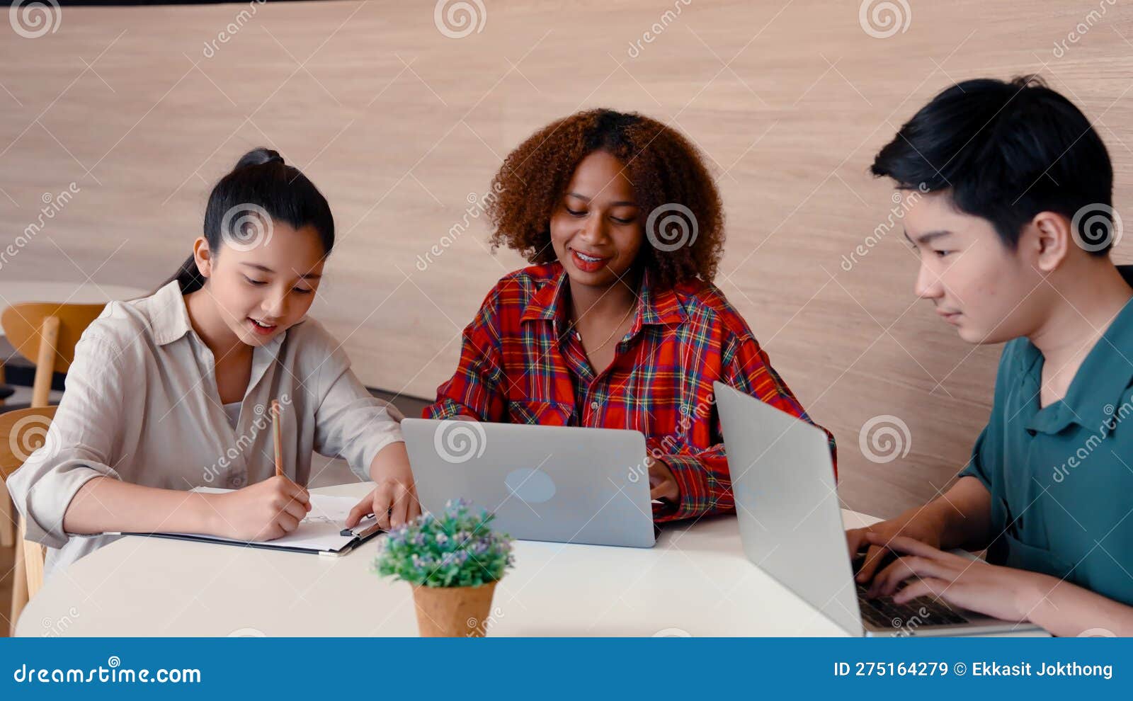 Three Young Students Sitting Together Doing Group Work, There are ...