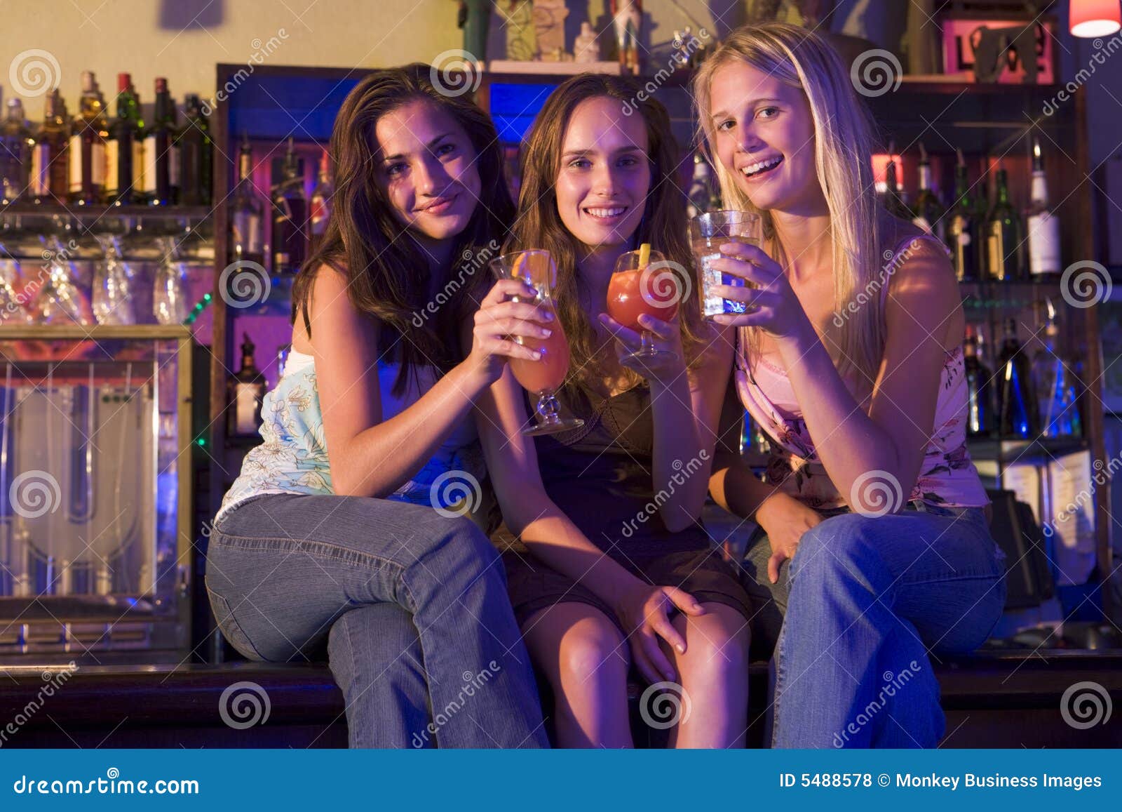 Three Young Women Sitting on a Bar Counter Stock Photo - Image of ...