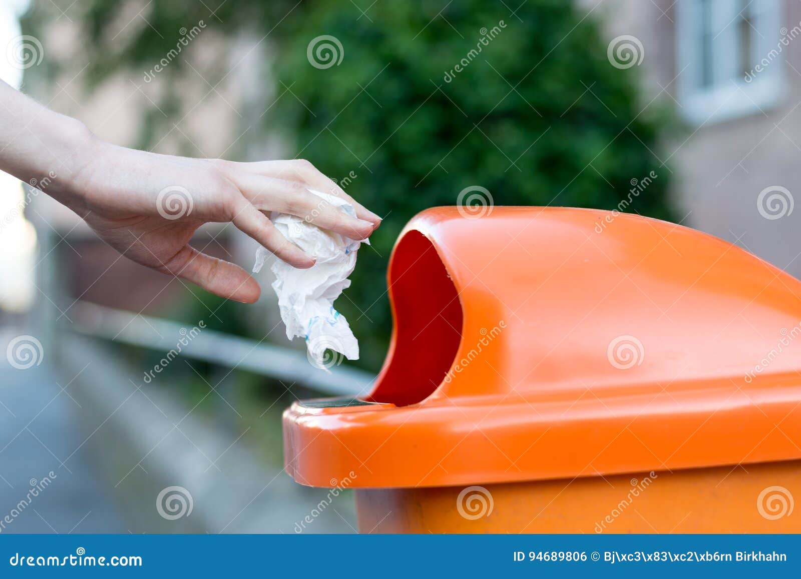 Throwing Waste into a an Orange Trash Can in the Street Stock Photo ...