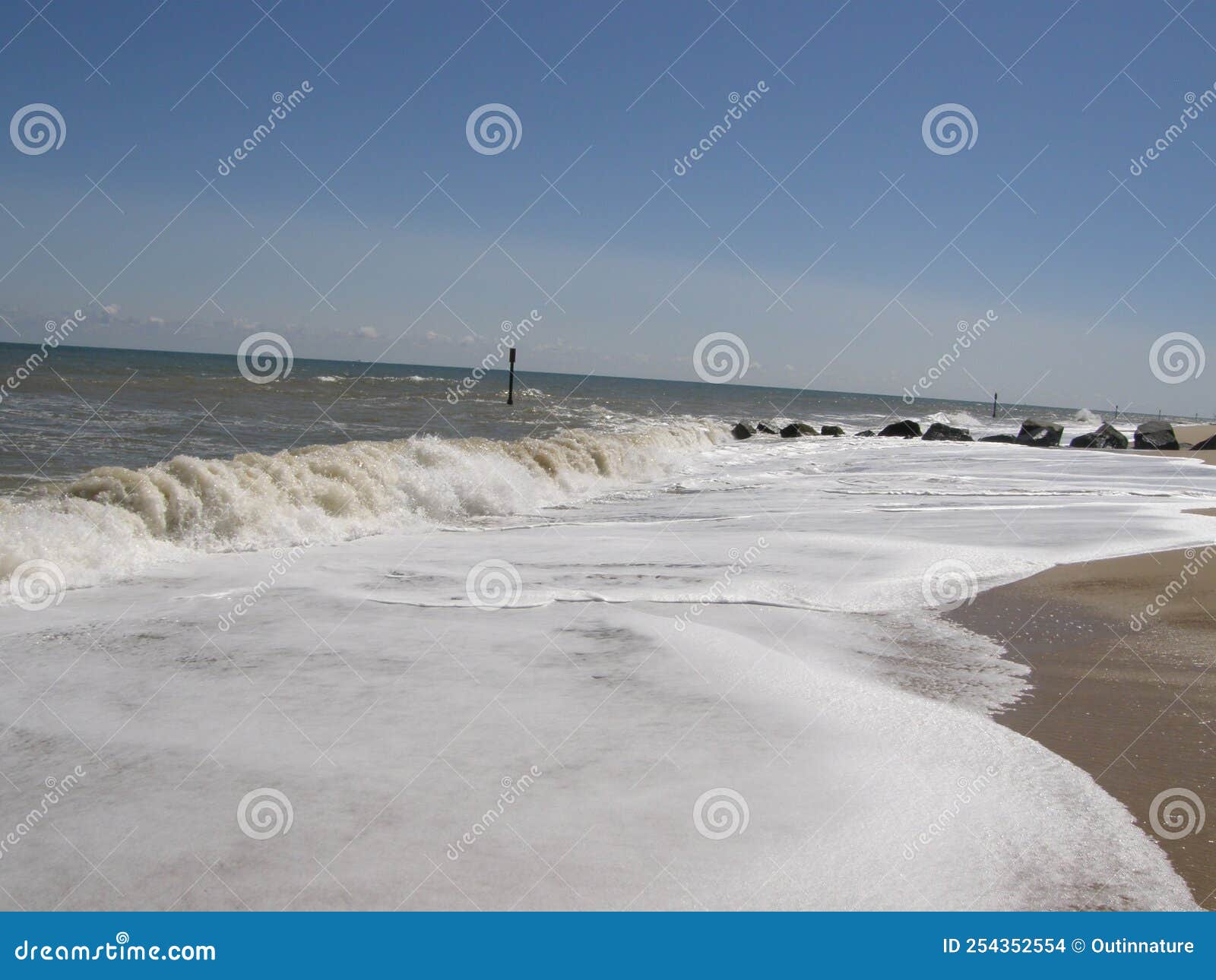 Clear Skies on a Sunny Beach As Ttde Rolls in Stock Photo - Image of ...