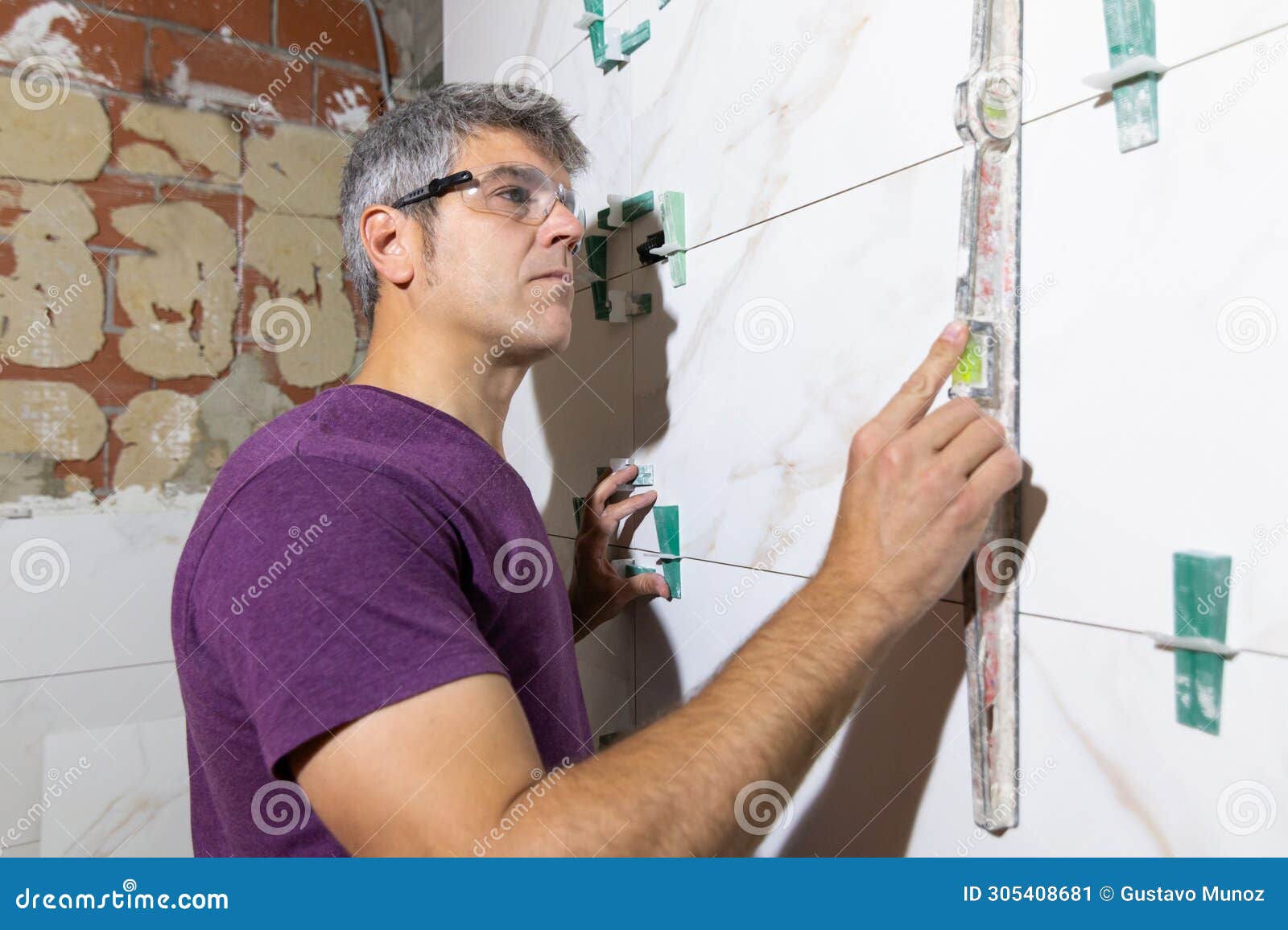 Tiler with Protective Glasses Checking the Installation with a Hand ...