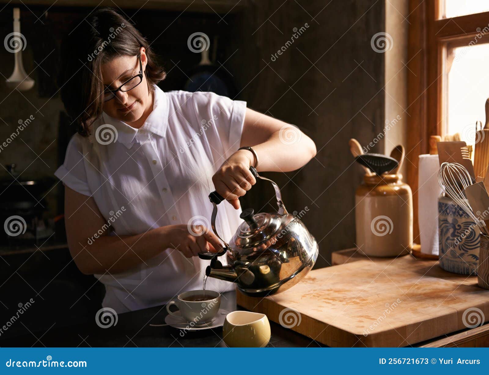Time To Unwind An Attractive Young Woman Making A Cup Of Tea In Her