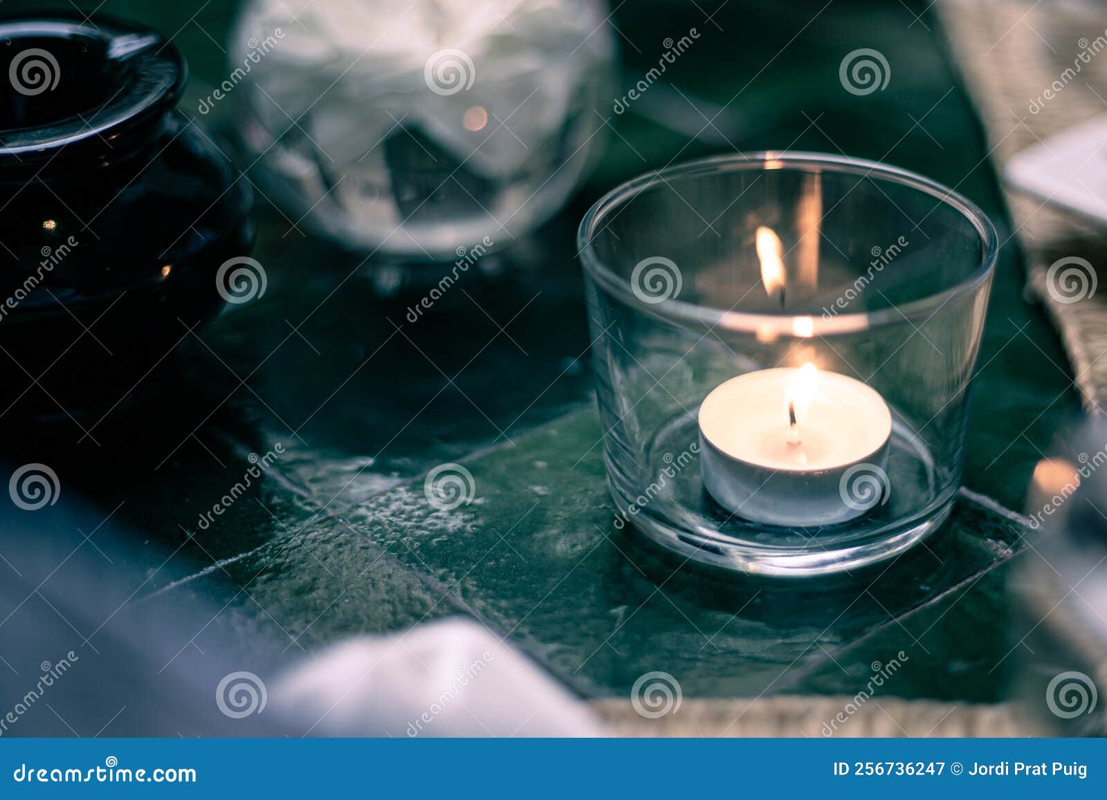 Tiny Candle Inside a Transparent Glass on a Green Tiled Table Stock ...