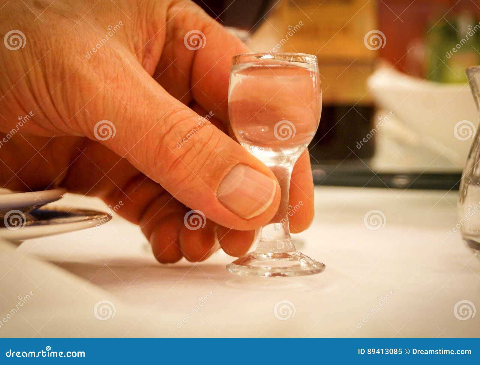 Tiny liqueur glass in hand stock image. Image of dinner - 89413085