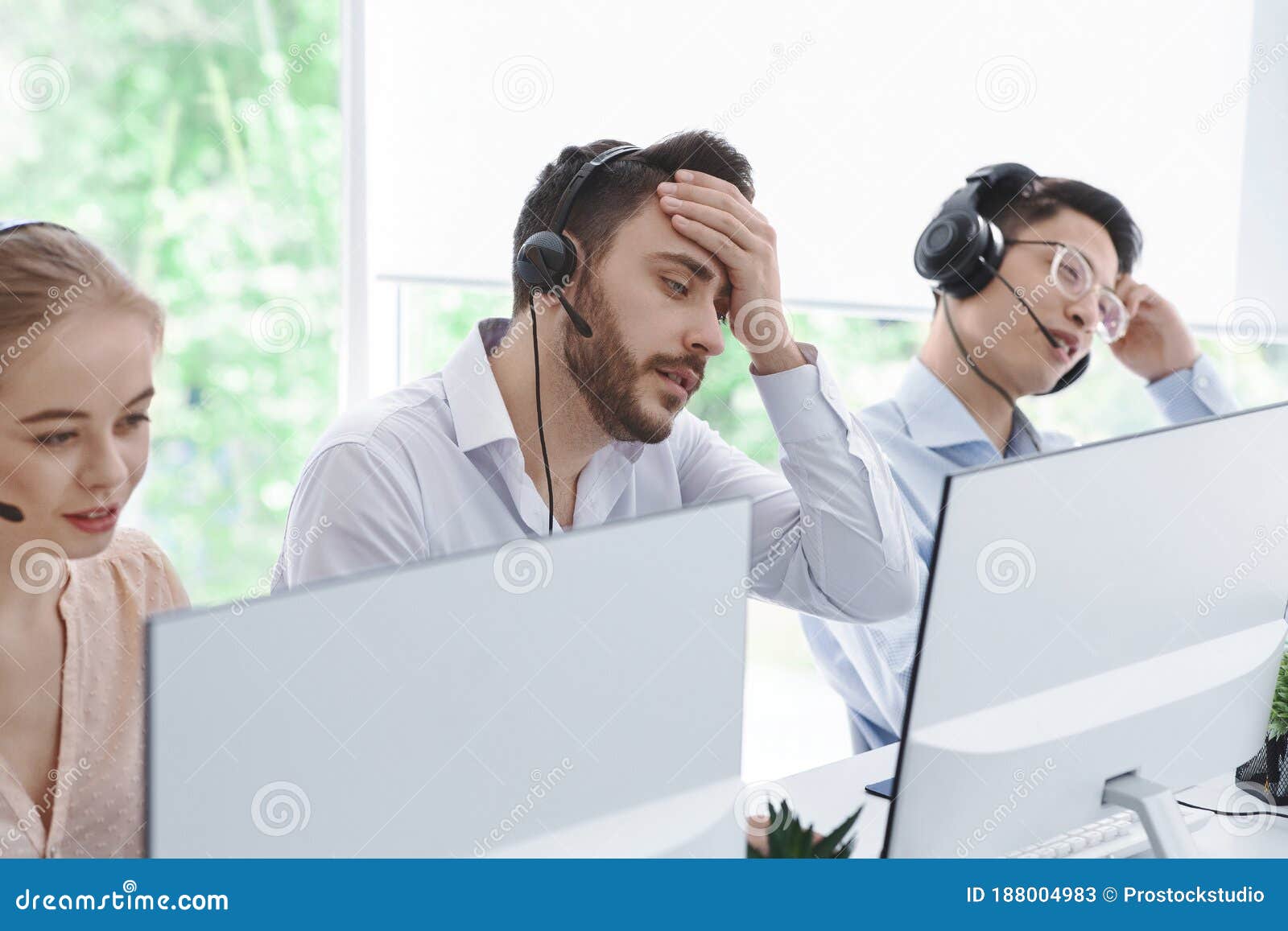 Tired Call Centre Operator and His Colleagues Communicating with ...
