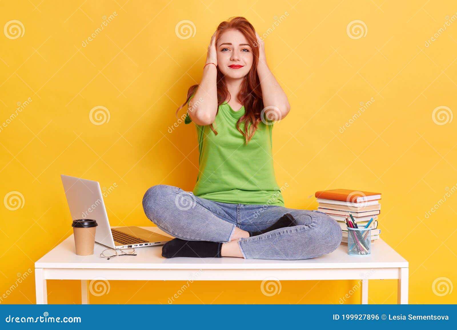 Tired Girl With Headache Sitting On Desk Desk With Crossed Legs Looks At Camera With Crazy