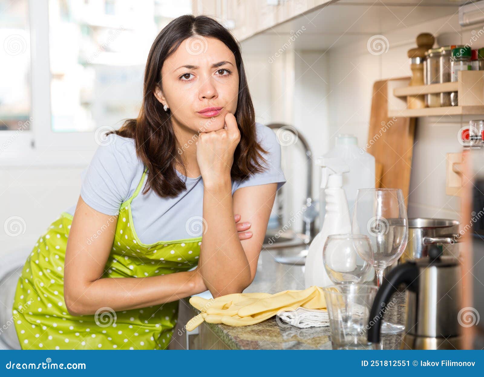 Tired Girl Housewife In Apron Holding Gloves At Kitchen Stock Image