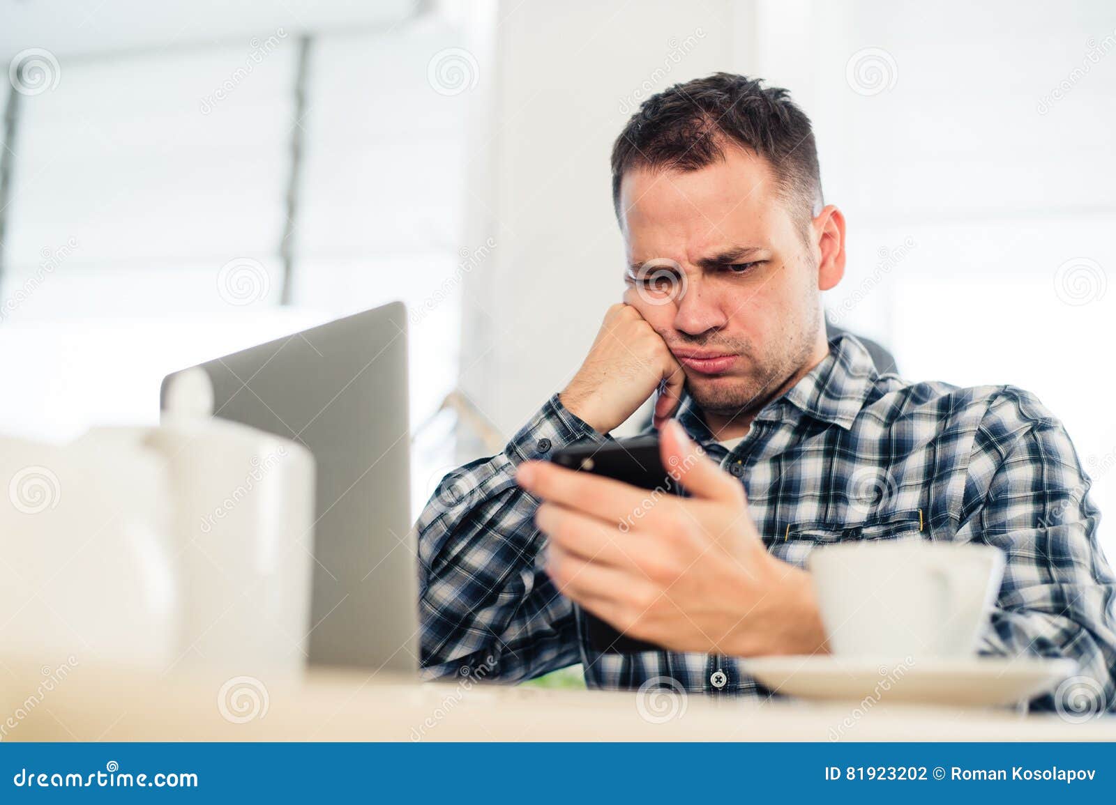 Tired Handsome Young Freelancer is Using a Mobile Phone while Working ...