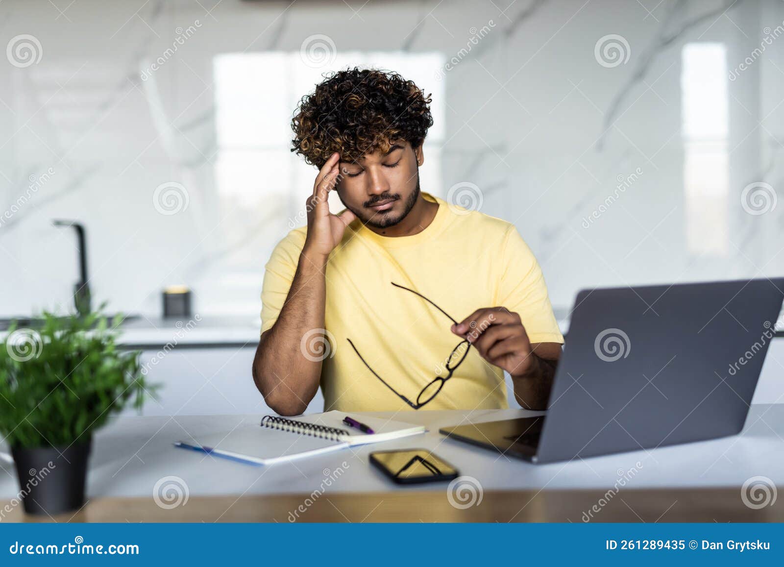 Tired Indian Man Holding Phone Working on Laptop Computer at the Table ...