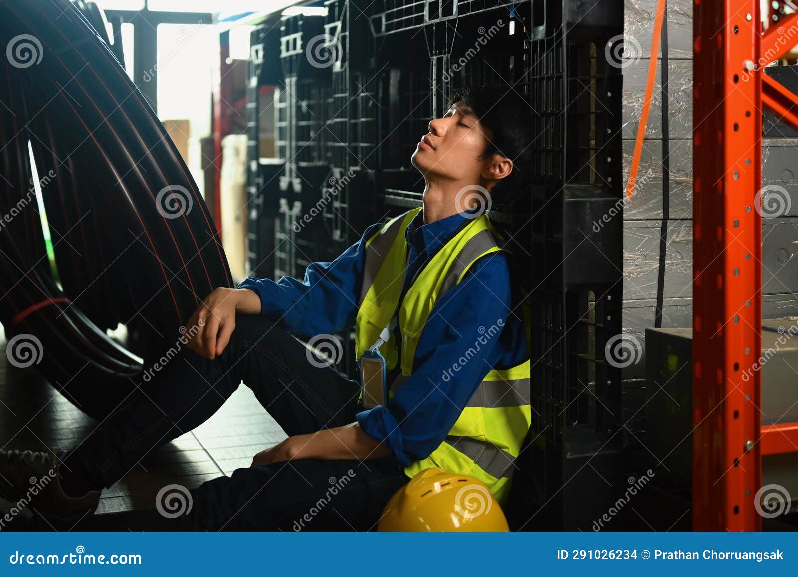 Tired Male Warehouse Worker Leaning Against Rack, Taking Break and ...