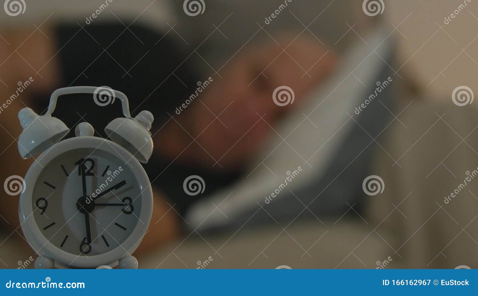 Tired Man Sleeping in the Bad with a Clock Alarm on the Table Stock ...