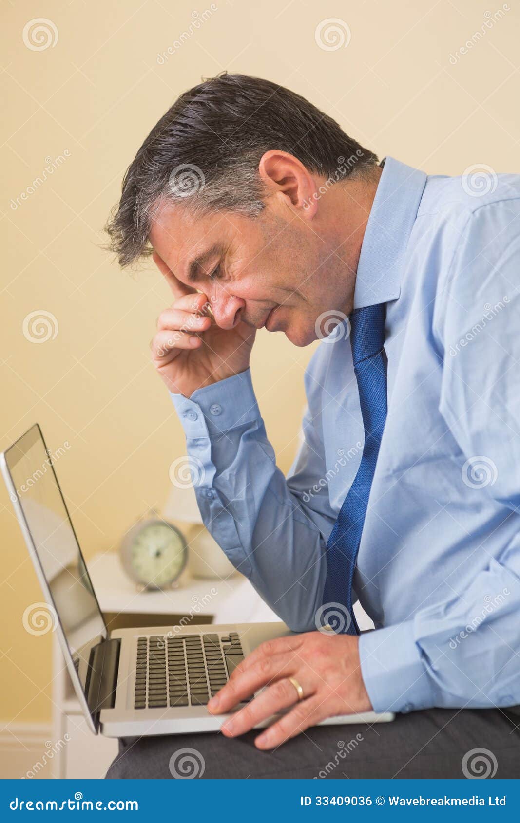 Tired Man Using a Laptop Sitting on a Bed Stock Photo - Image of laptop ...