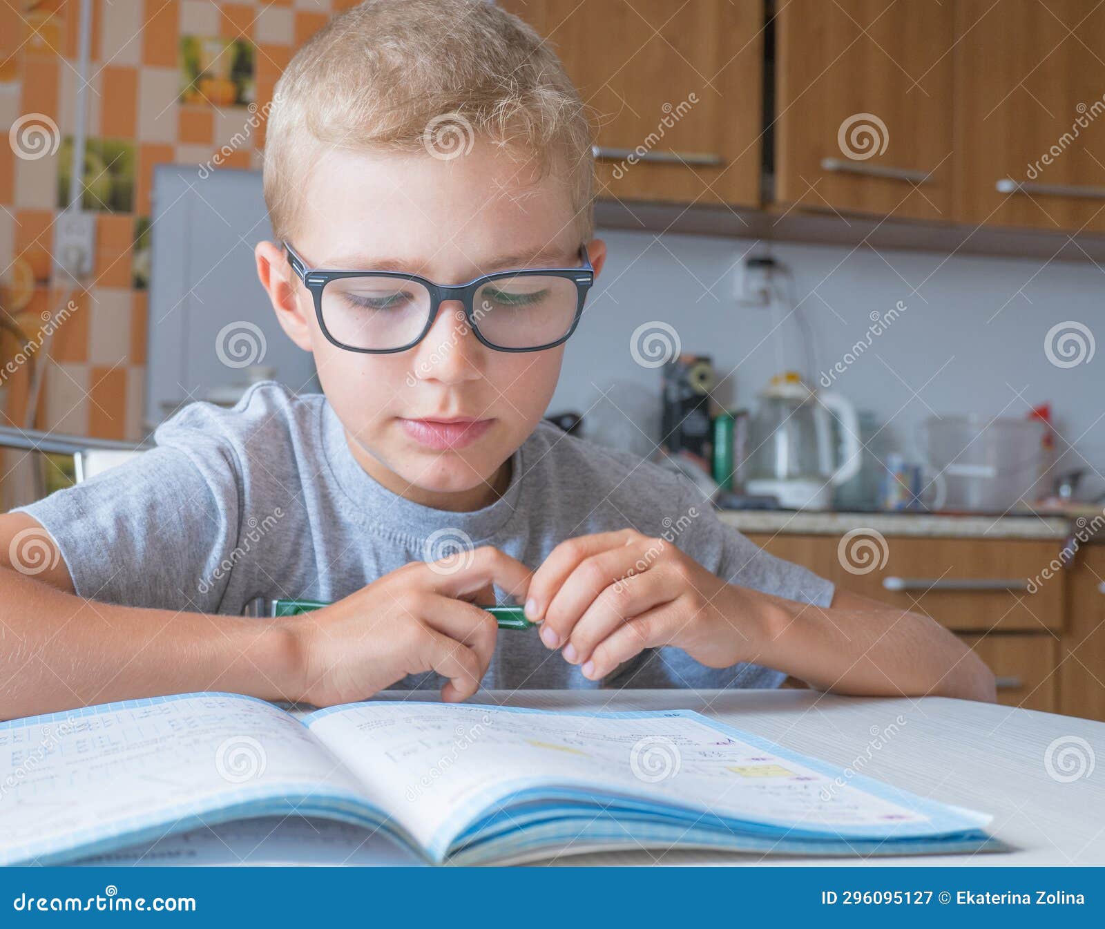Tired Sad Little Child Boy Sits at a Table in the Kitchen and Writes ...