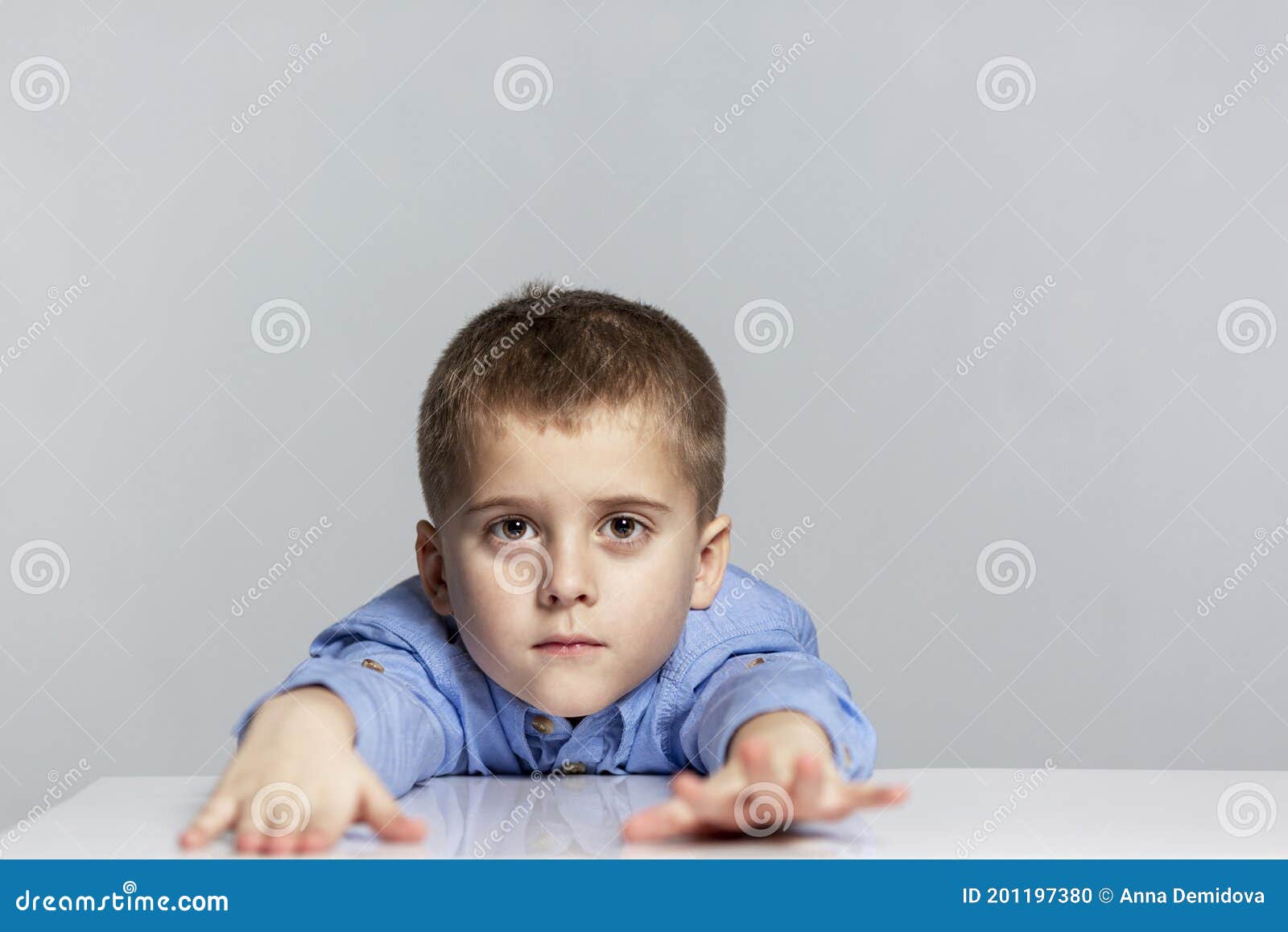A Tired Schoolboy Boy Sits at the Table with His Arms Outstretched ...