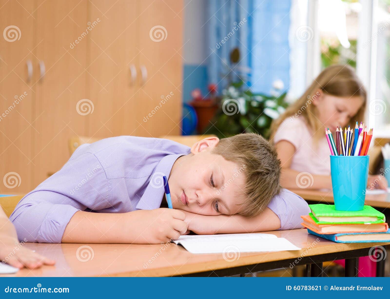 Tired Schoolboy While Doing Homework. Cute Pupils Writing At Desk In ...
