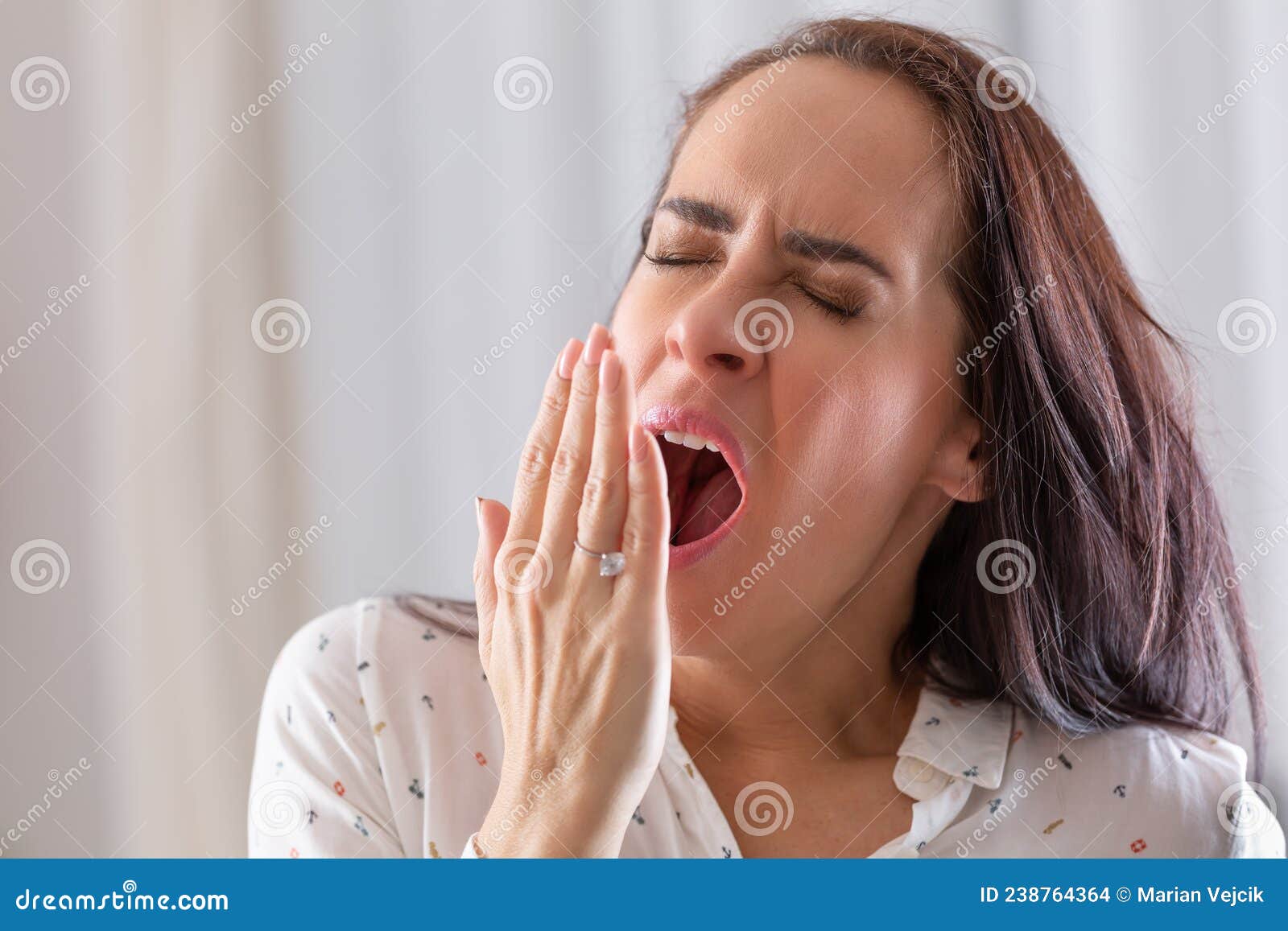 Tired And Sleepy Woman Yawns With Mouth Wide Open And A Hand In Front