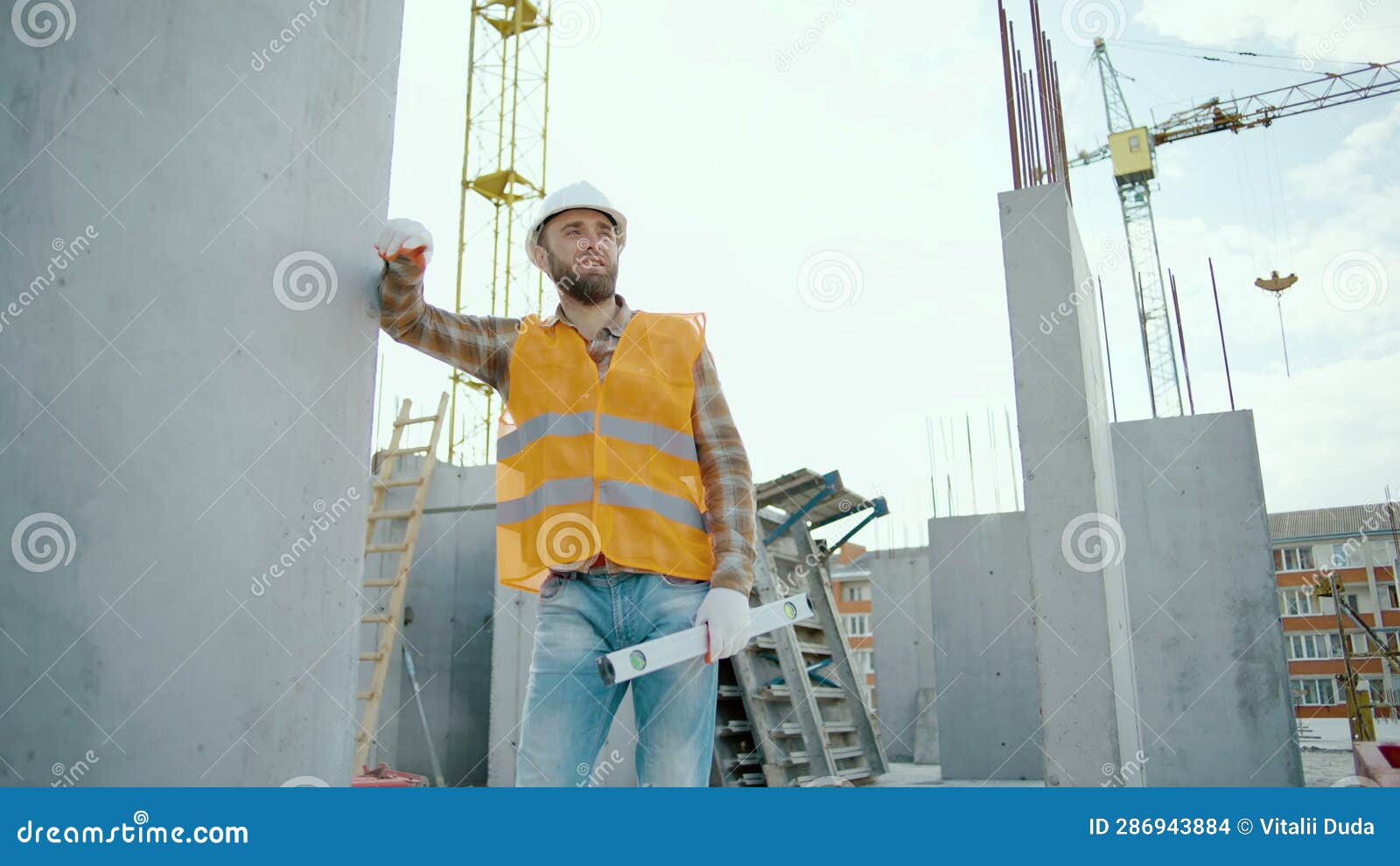 A Tired Worker at a Construction Site Rests His Hand on the Wall after ...