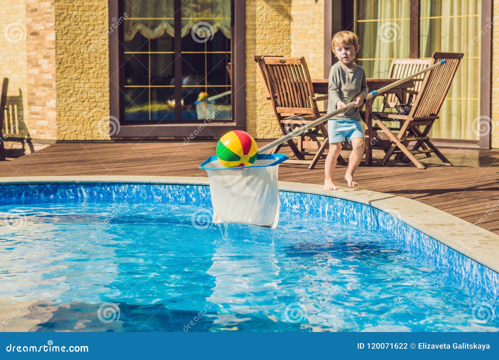 The Toddler Boy Cleans the Pool and Pulls the Ball Out of the Po Stock ...