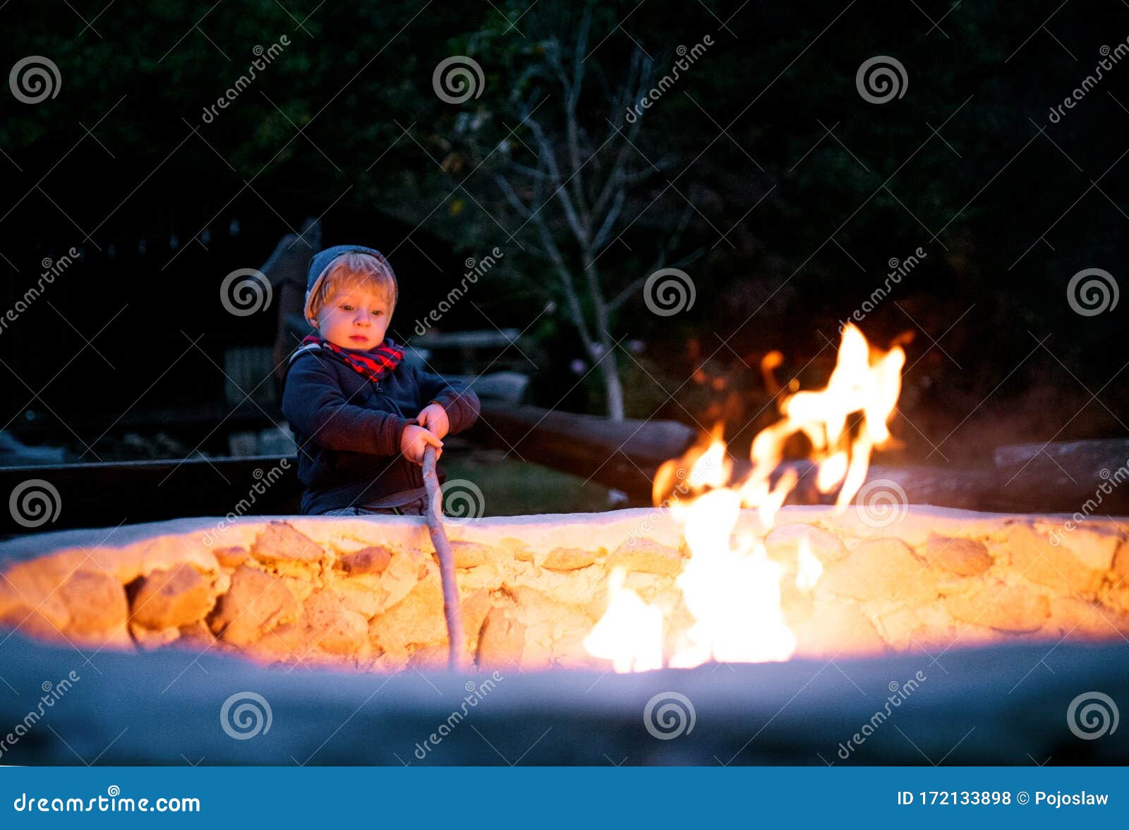 A Toddler Boy Standing and Playing by Open Fire Outdoors in Garden in ...