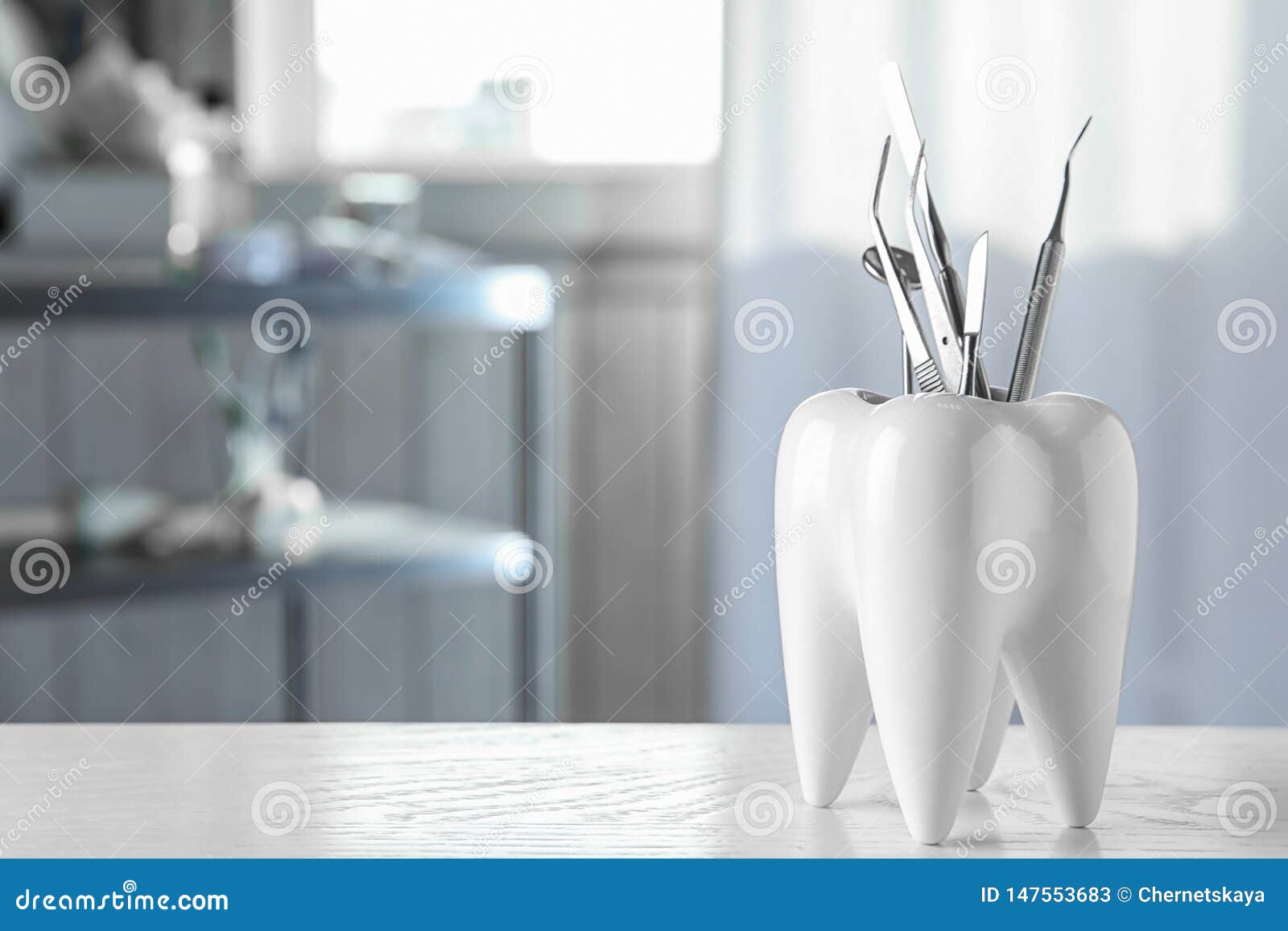 Tooth Shaped Holder with Professional Dentist Tools on Table in Clinic ...