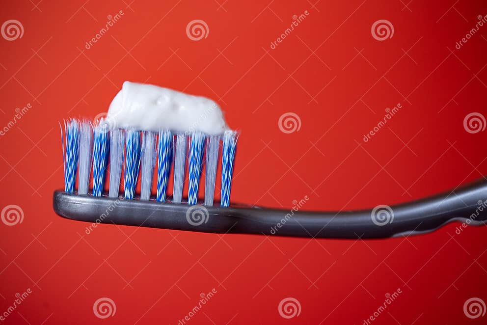 Toothbrush with Blue Bristles and Toothpaste on a Red Background Stock ...