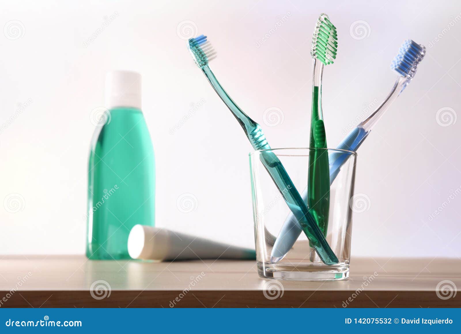 Toothbrushes in Glass Cup on Table and Toothpaste and Mouthwash Stock ...