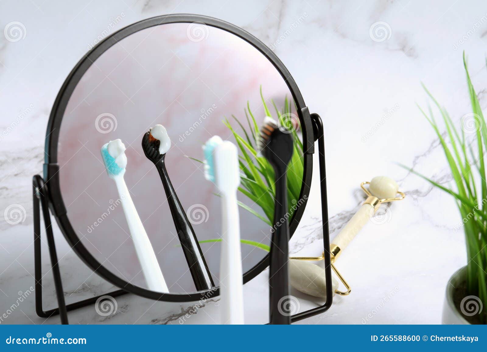 Toothbrushes with Paste, Mirror and Facial Roller on White Marble Table ...