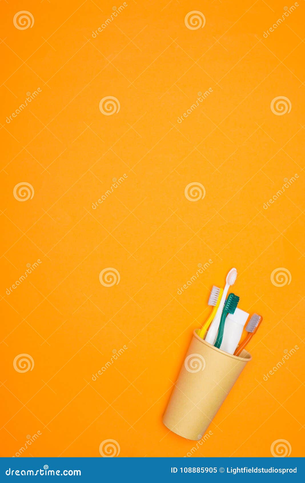Toothbrushes and Toothpaste in Paper Cup, Isolated on Orange Stock ...