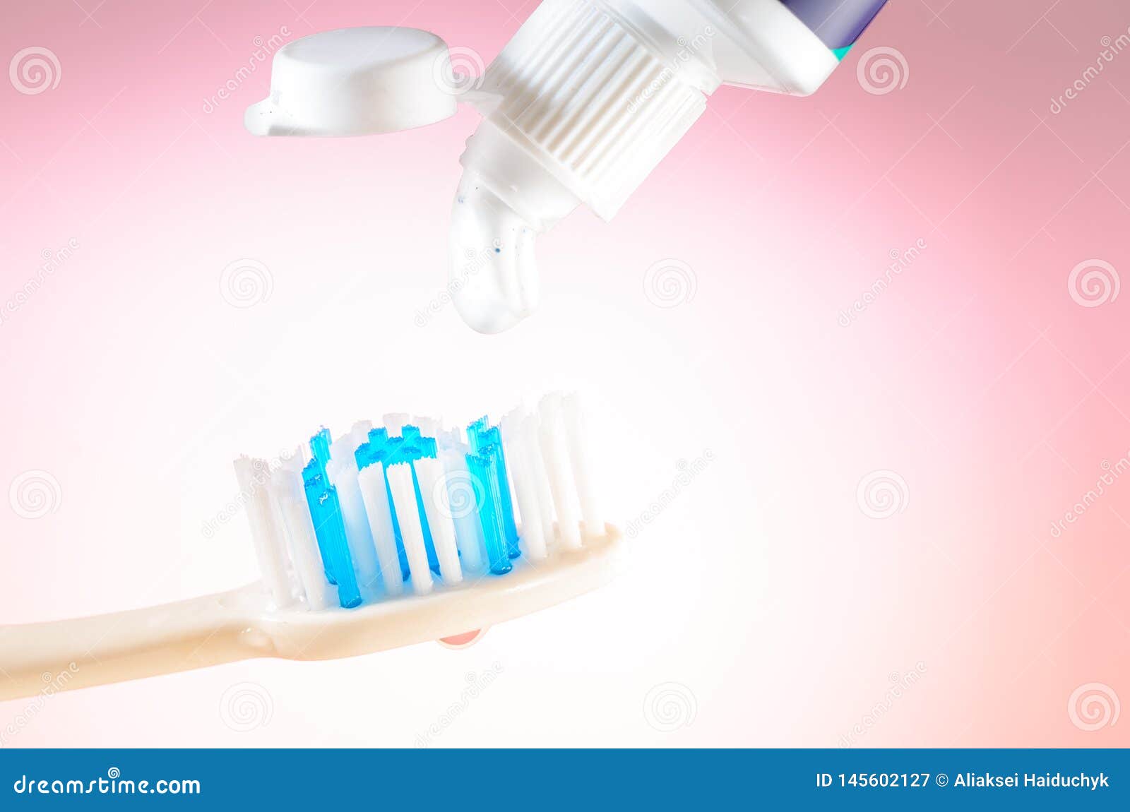 Toothpaste Squeezed from Tube Onto Brush on a Pink Background, Close Up ...