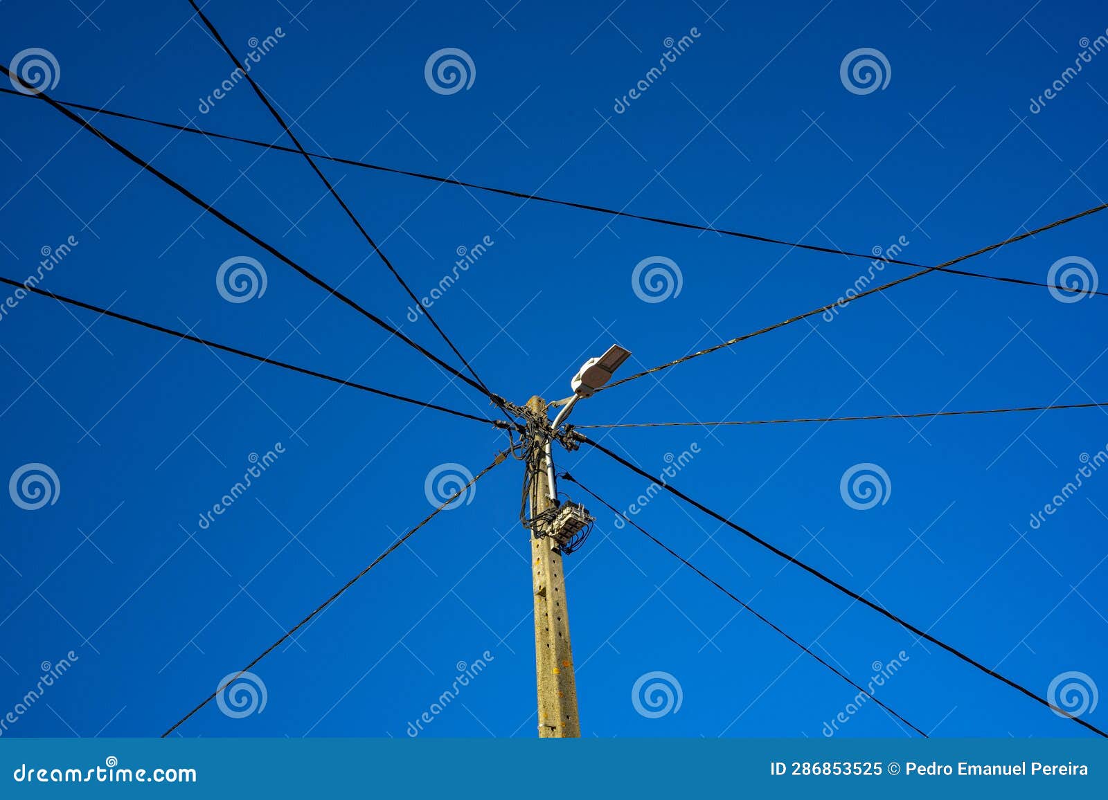 Top of Street Light Pole with Tangle of Electrical Cables Against Blue ...