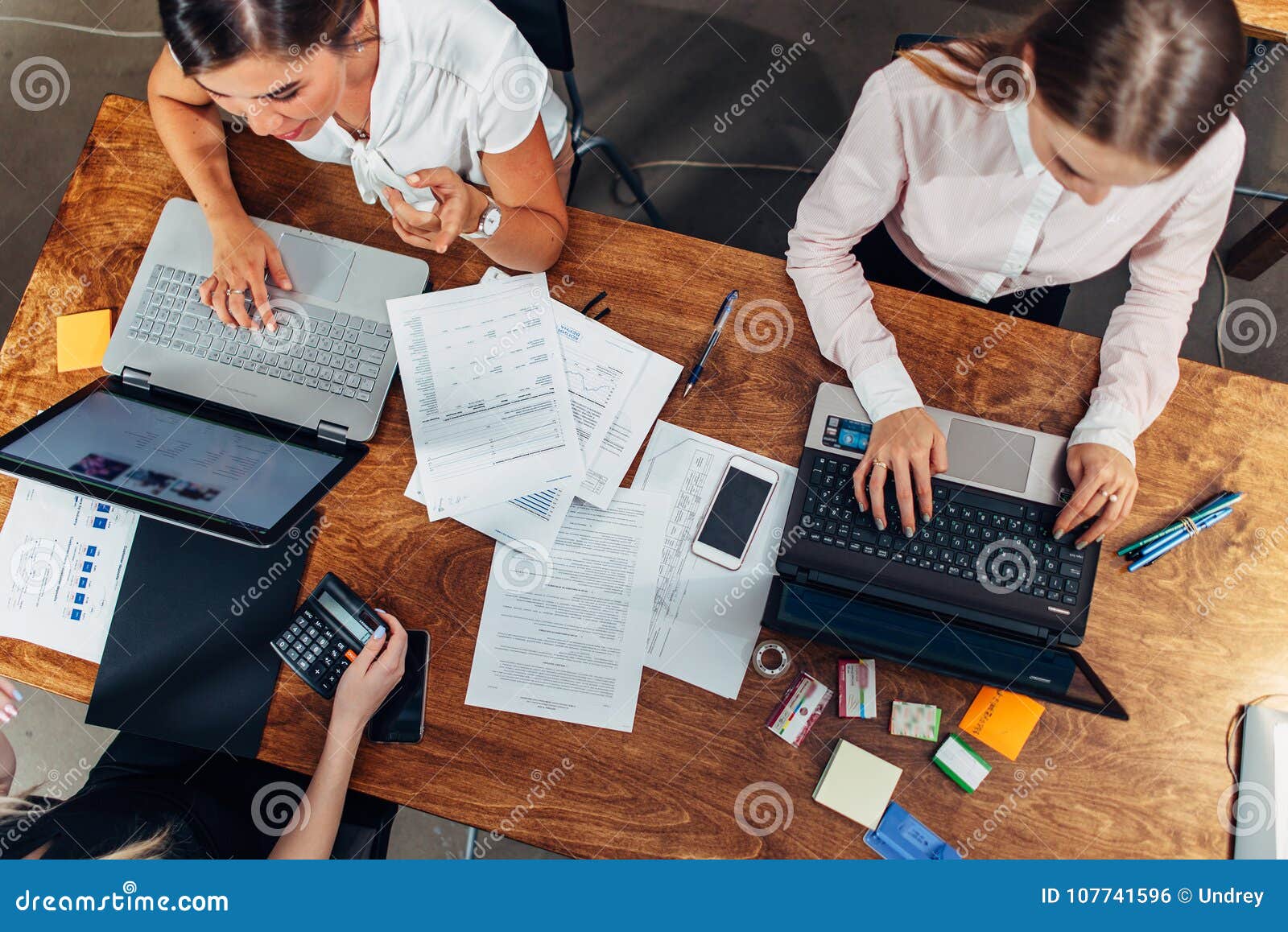 Top View of Three Women Working with Documents Using Laptops Sitting at ...