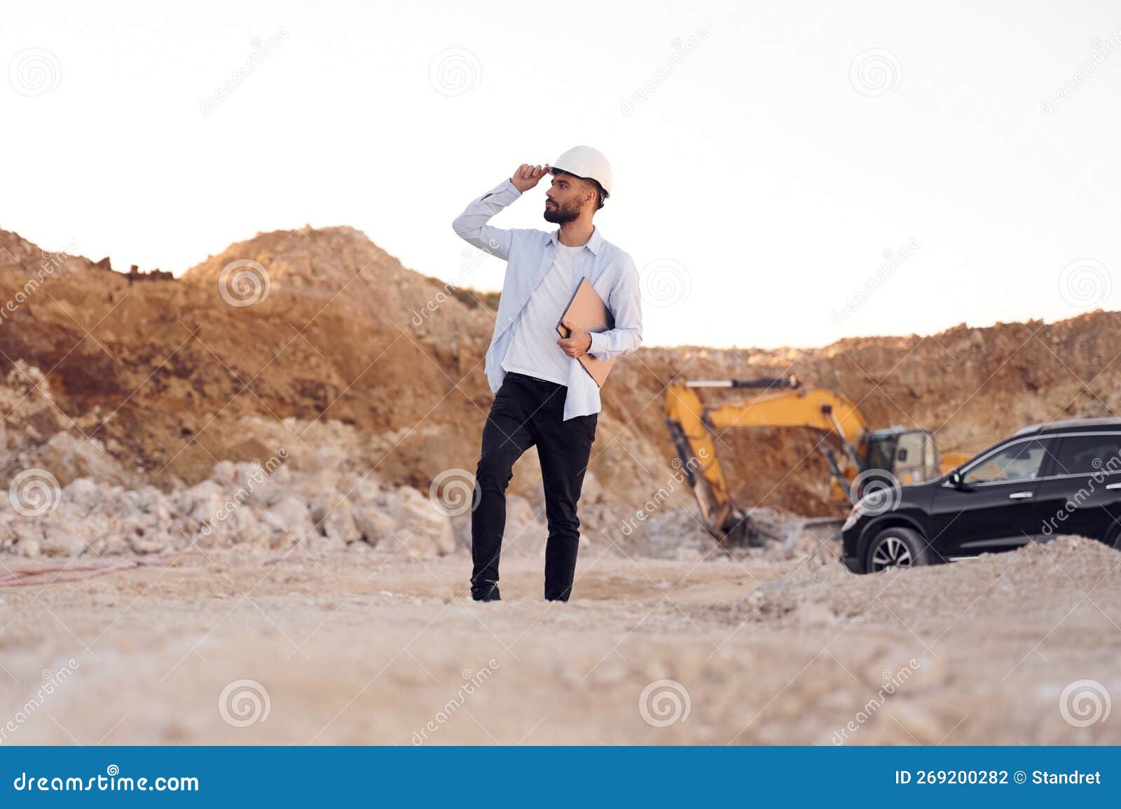 Touching Hard Hat and Holding Laptop. Man in Uniform is Working in the ...