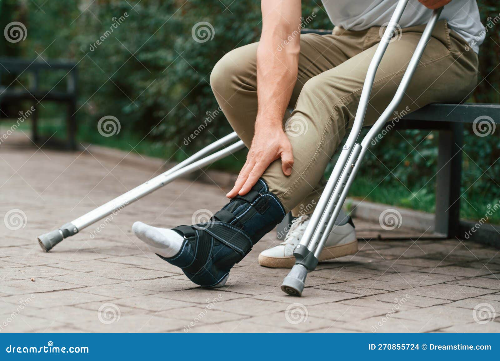 Touching the Leg. Man with Crutches is in the Park Outdoors Stock Photo ...