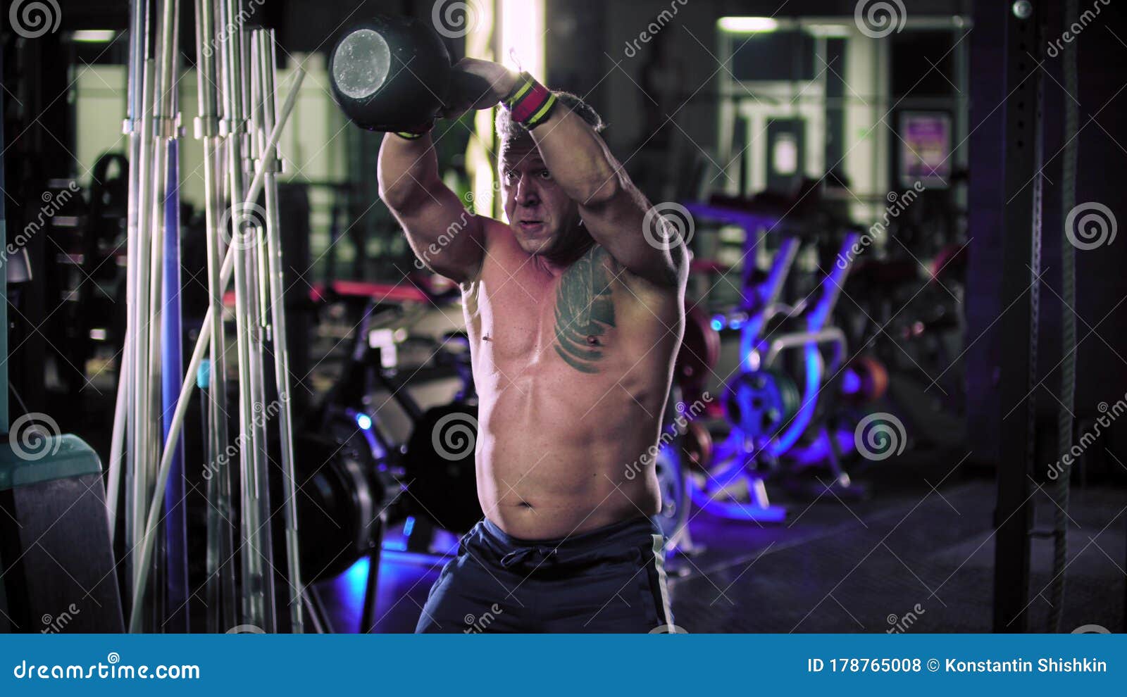 A Tough Man Bodybuilder with a Tattoo Pulls a Kettlebell in the Gym ...