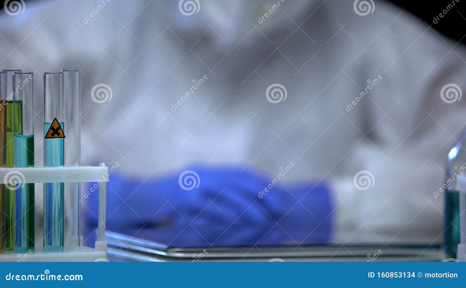 Toxic Lab Worker Examining Harmful Liquid and Reading Notes on Tablet ...