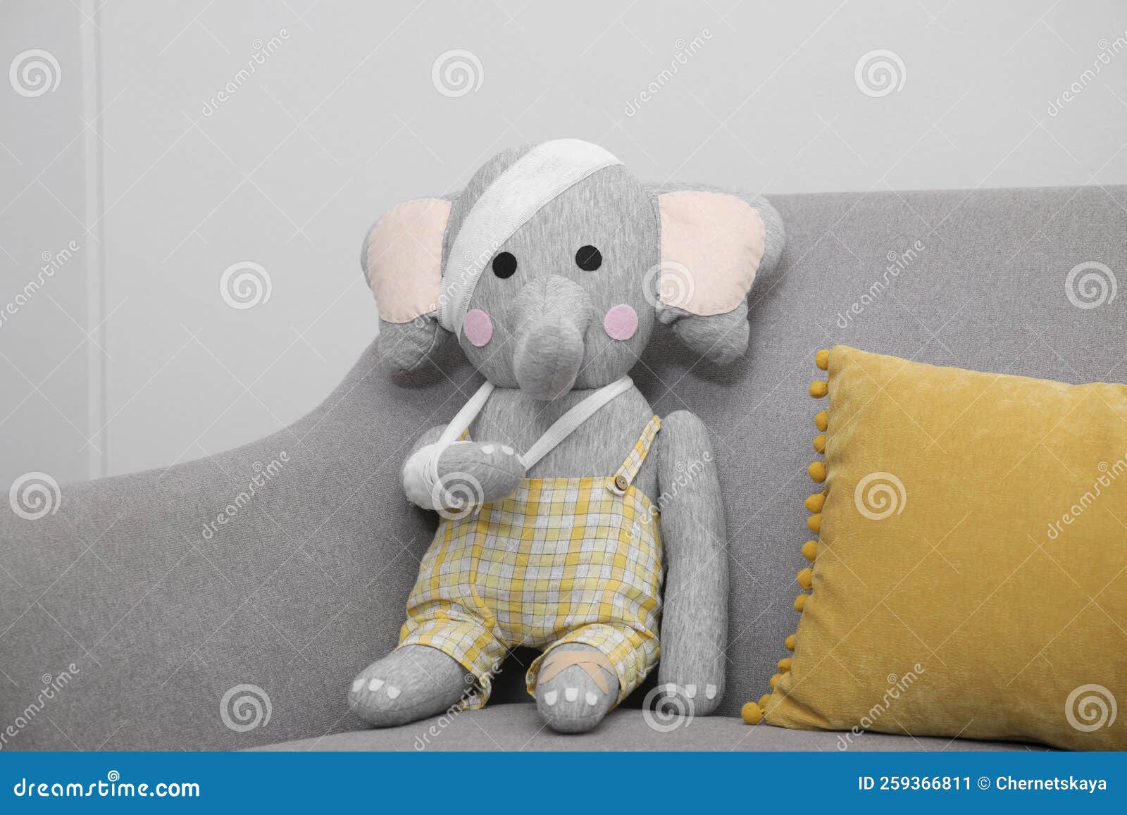 Toy Elephant with Bandages Sitting on Sofa Near Light Wall Stock Image ...