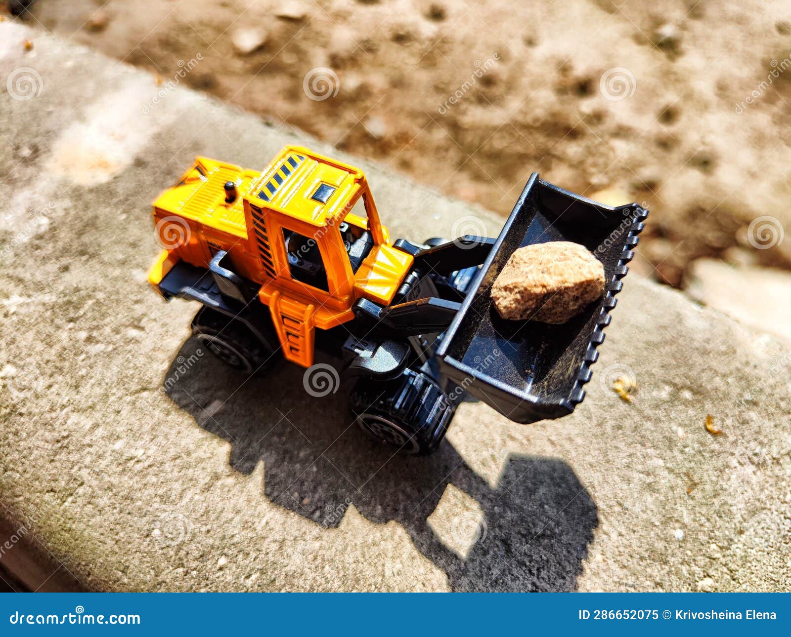 Toy Yellow Tractor or Excavator with a Bucket during Operation. Road or ...