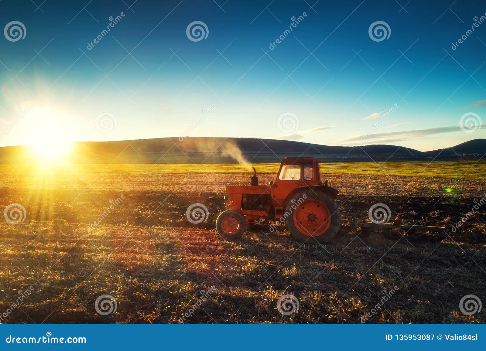 Tractor Cultivating Field at Spring, Sun Sets Dawn Behint the Hills ...