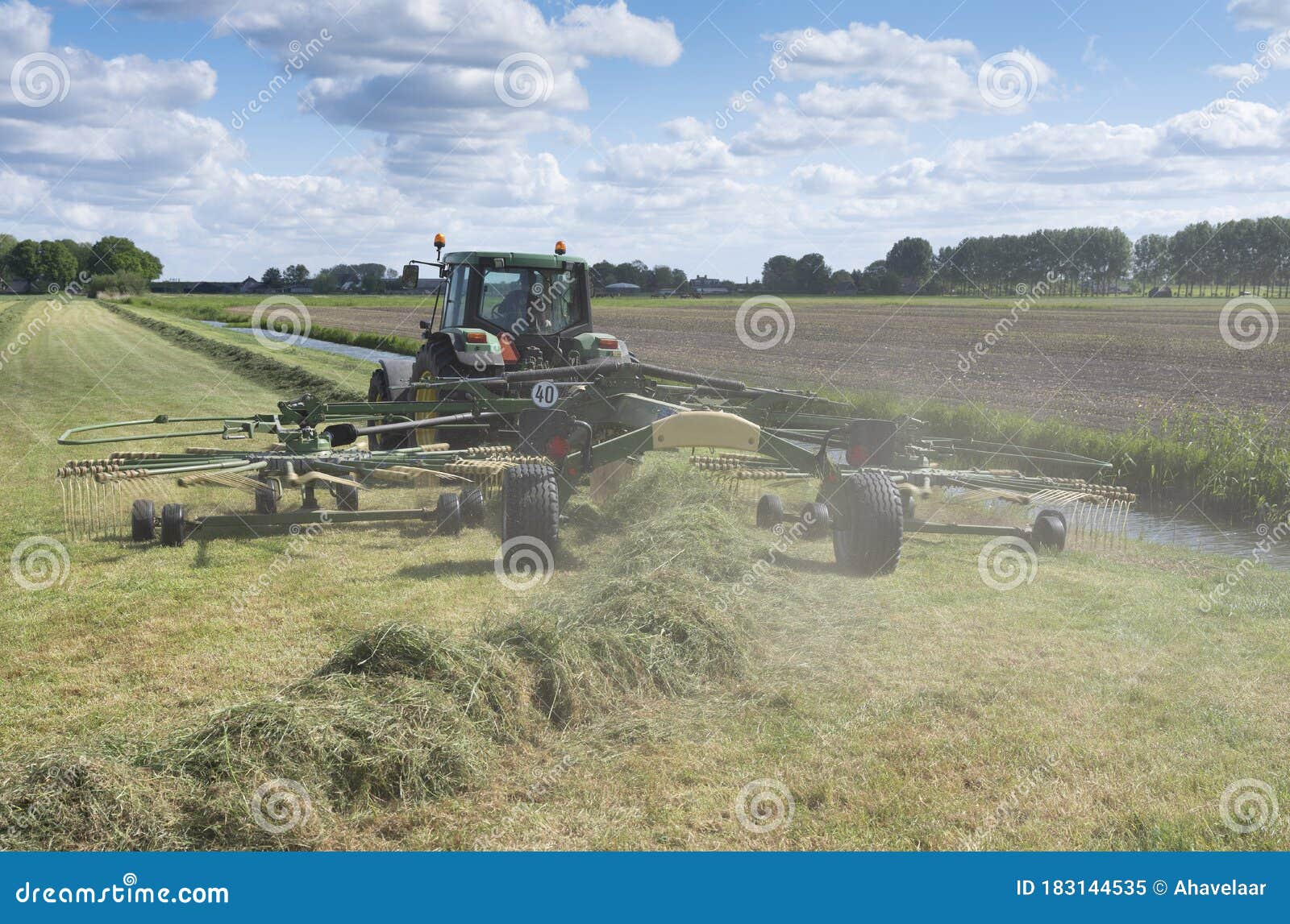Tractor in Field with Grass Tedder during Hay Harvest in the ...
