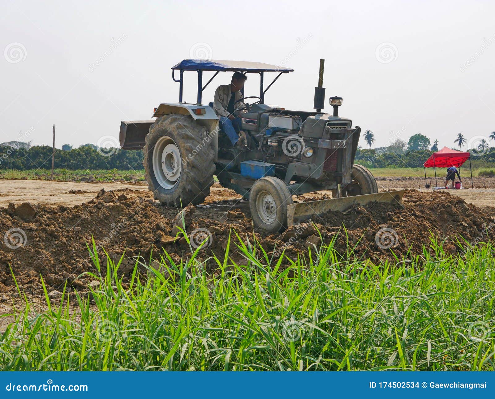 A Tractor Mounted with Front Grader is Preparing an Entrance Ramp ...