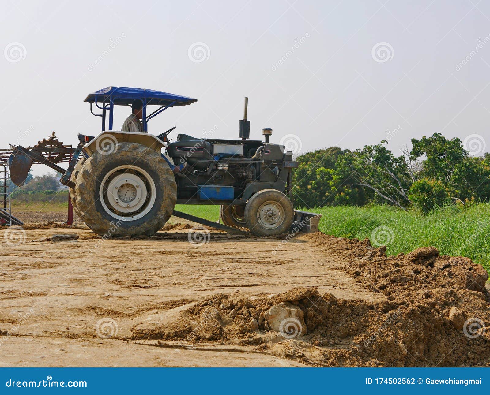 A Tractor Mounted with Front Grader is Preparing an Entrance Ramp ...