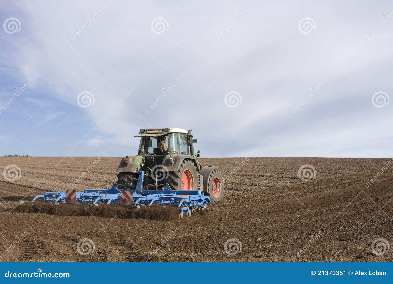 Tractor Ploughing Field With Blurry Farm In The Background Royalty-Free ...