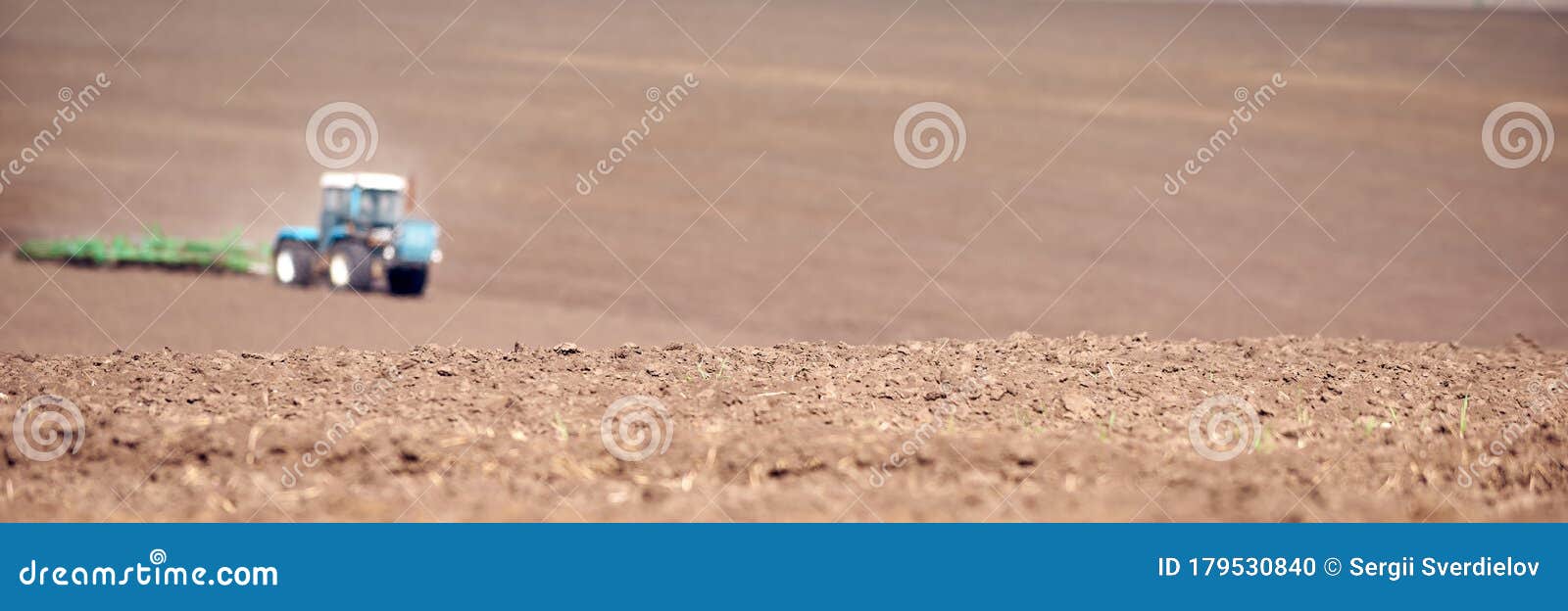A Tractor Plowing and Sowing in the Field. Panoramic Format Stock Photo ...