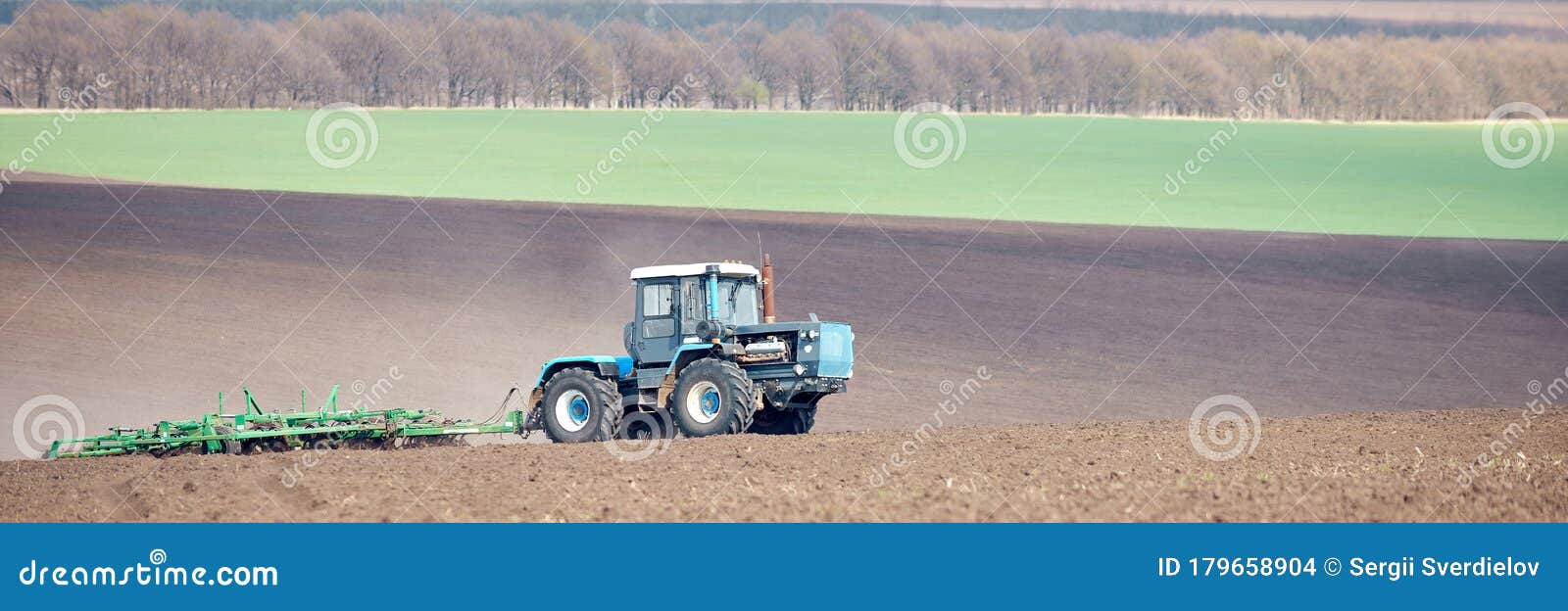 A Tractor Plowing and Sowing in the Field. Panoramic Format Stock Photo ...