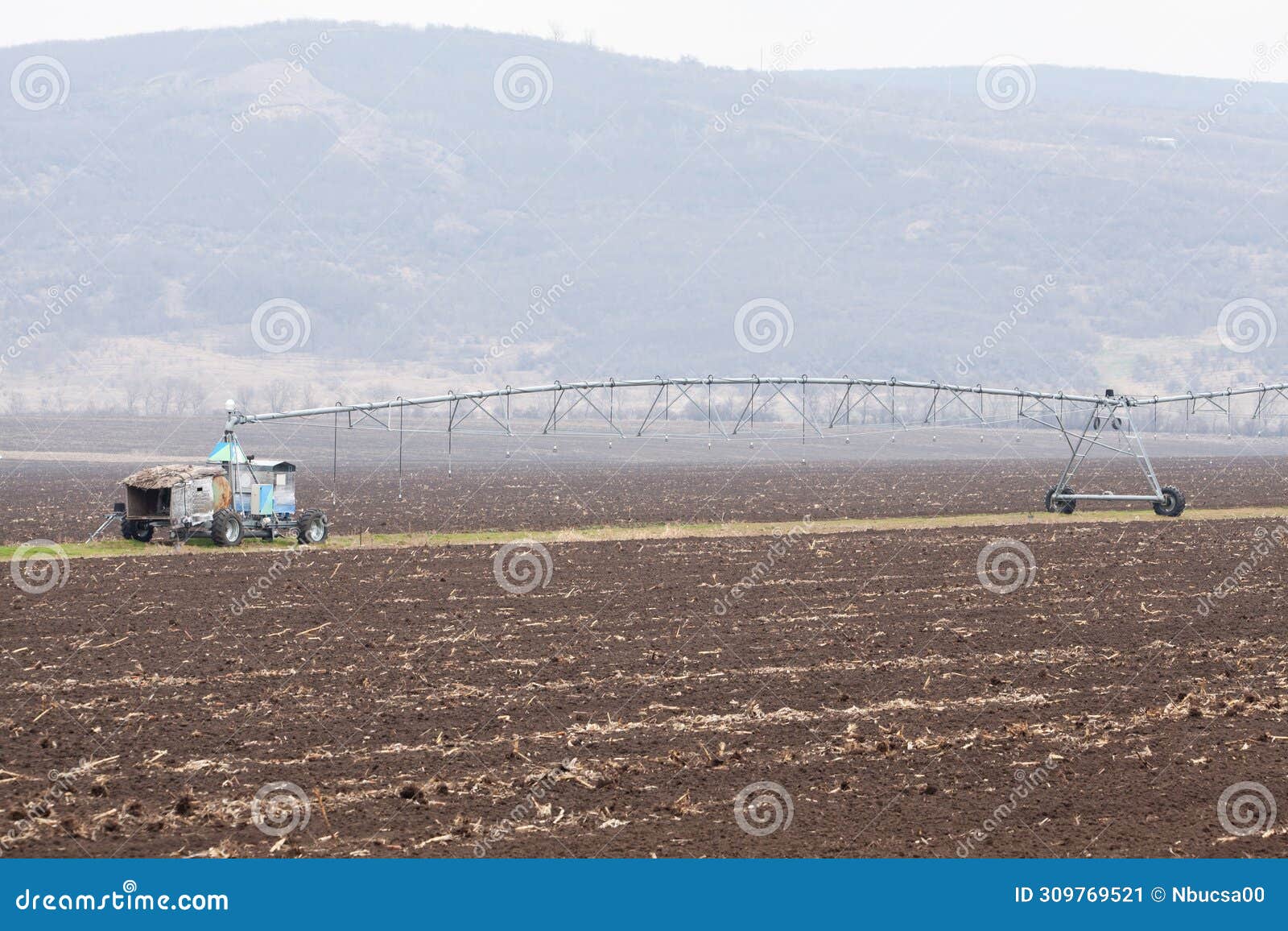 A Tractor Plows a Field with Irrigation System Under a Vast Sky Stock ...