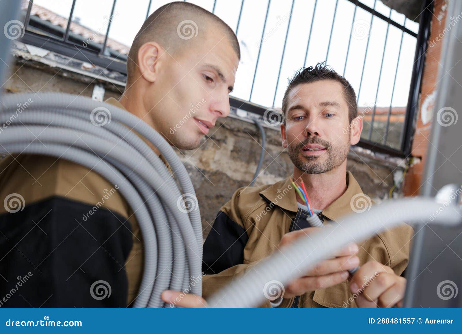 Tradesman Showing Cable Trunking To Young Apprentice Stock Image - Image of holding, industrial ...
