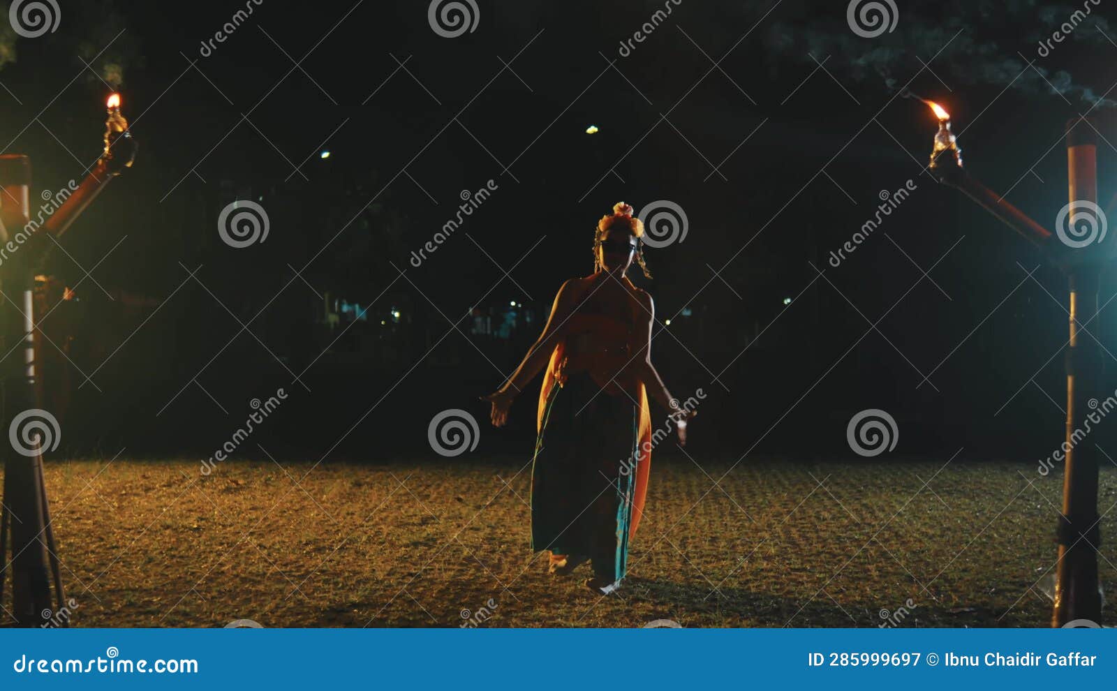 A Traditional Asian Dancer is Dancing among the Flames of Torches that ...